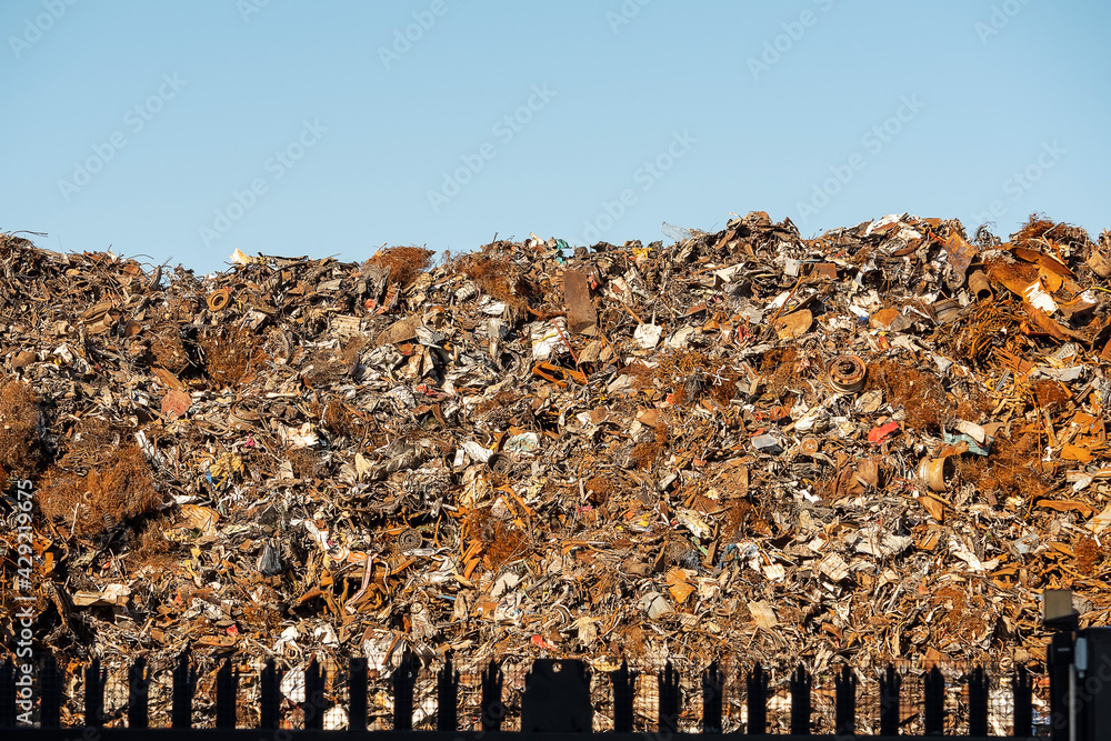 Pile of old rusty metal bits behind fence. Recycle industry concept ...