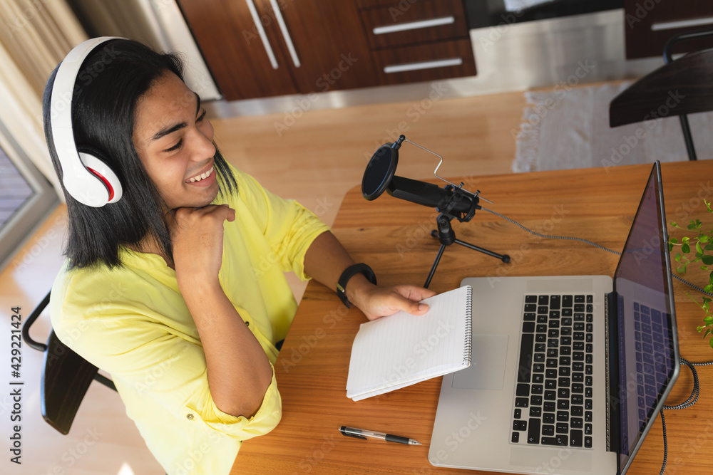 Mixed race transgender woman wearing headphones making podcast using ...