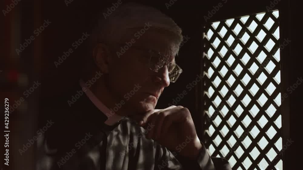 Lockdown of elderly Caucasian priest wearing robe, white collar and ...