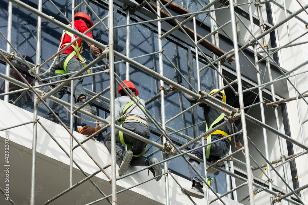 Construction workers on scaffolding doing final finishing works ...