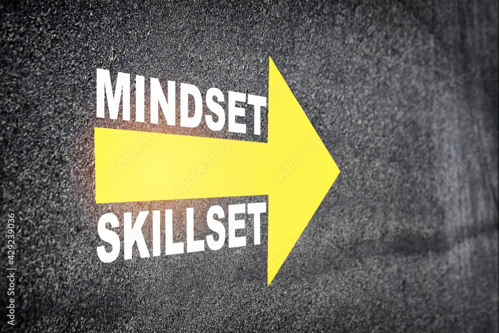 Mindset and skillset written on asphalt road surface with yellow arrow ...