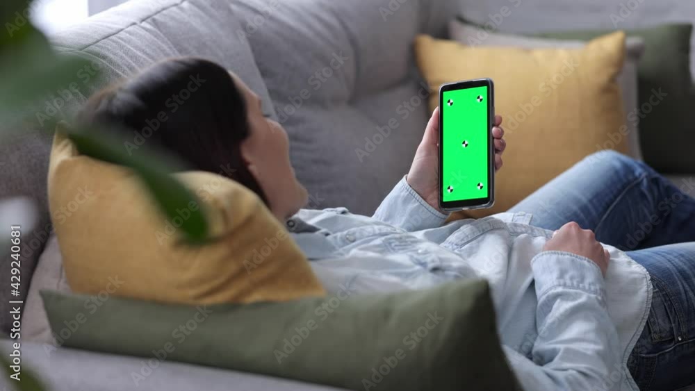 Young woman making video call at smartphone camera green screen with ...