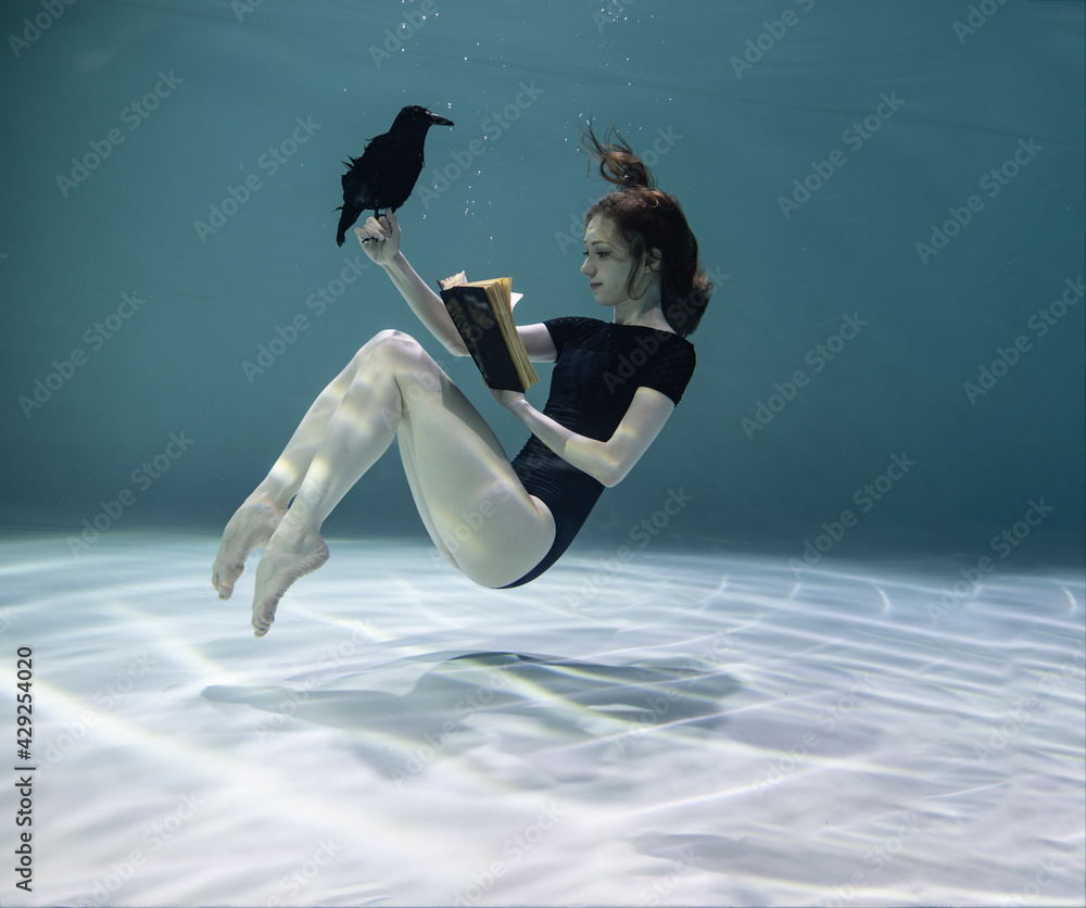 beautiful girl in a red swimsuit reads an interesting book underwater ...