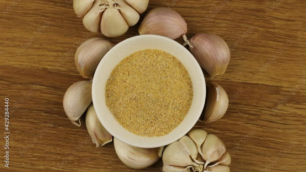 Ground garlic powder on the saucer and heads of garlic around rotates ...