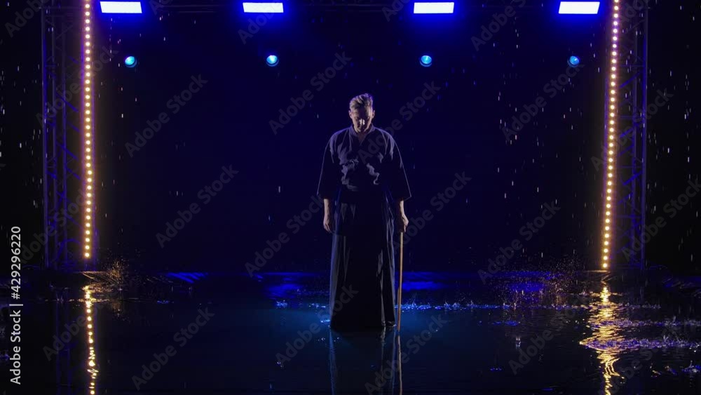 Portrait of man in a black kimono with bamboo fighting sword in his ...