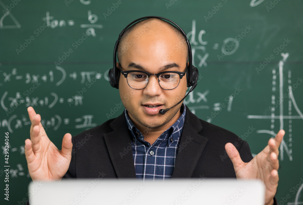 Indian young teacher man sitting wearing headset teaching online video ...
