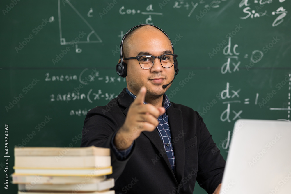 Indian young teacher man looking at camera sitting teaching online ...