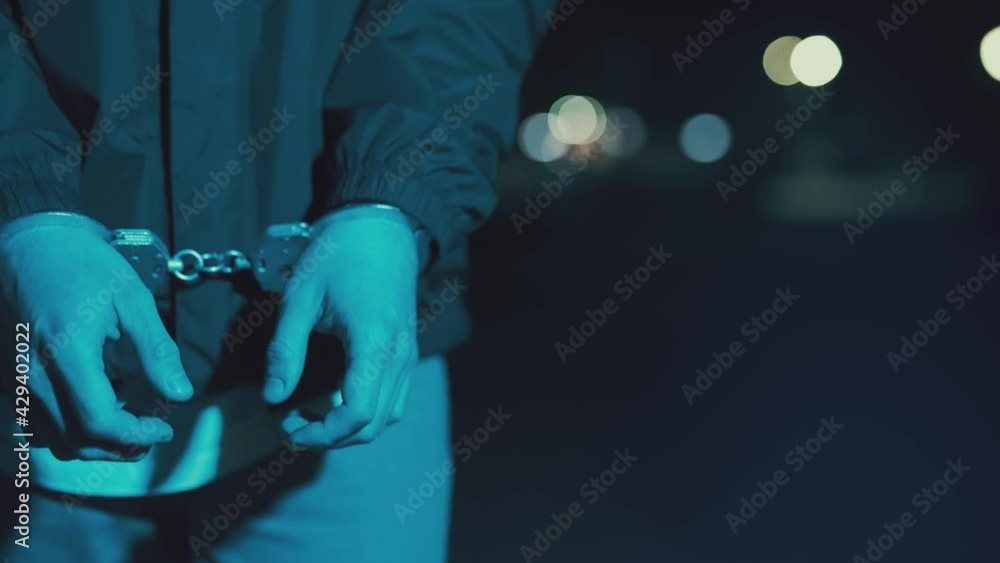 Close-up of severe policeman leading a handcuffed dangerous criminal to ...