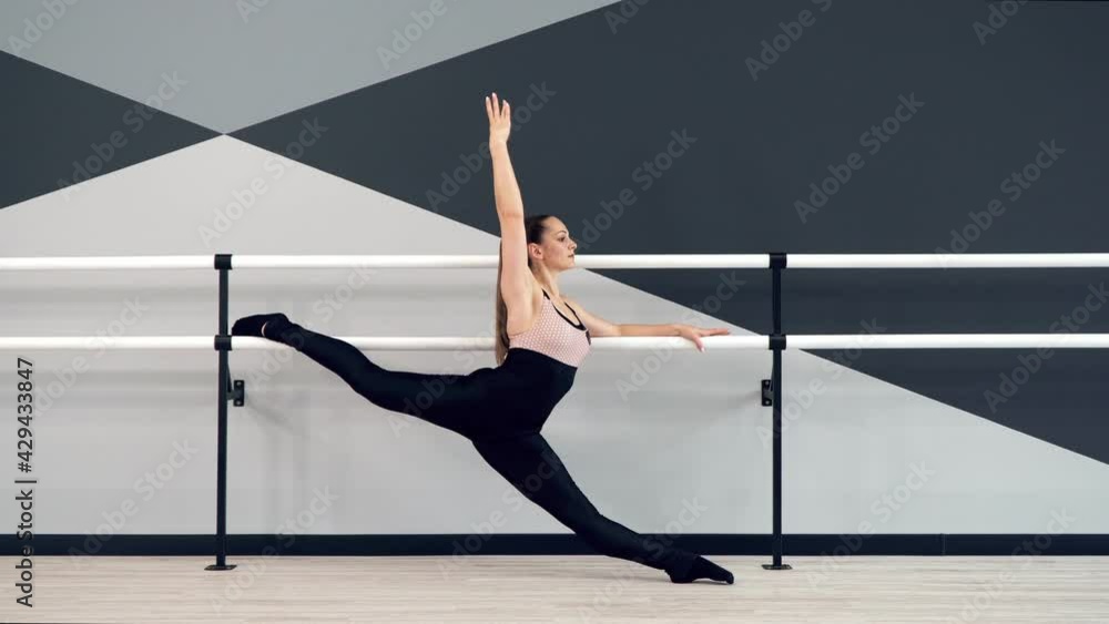 Side view of gorgeous brunette woman stretching leg on handrail, doing ...