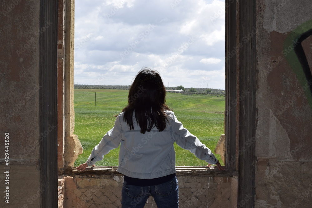 Girl looking out of window, dressed in jeans. looking at the horizon ...
