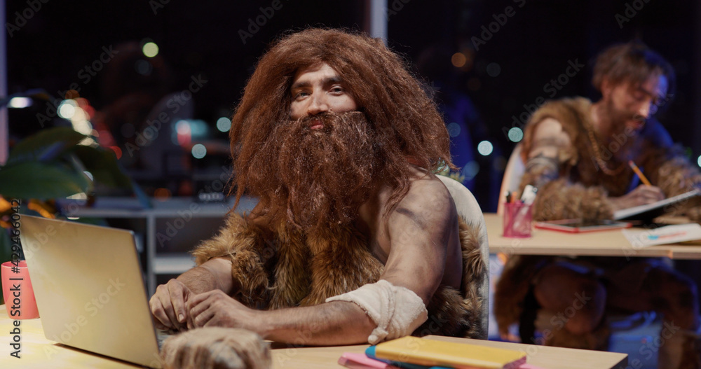 Portrait of Savage Neanderthal Tribesman Sitting in Office Doing Modern ...