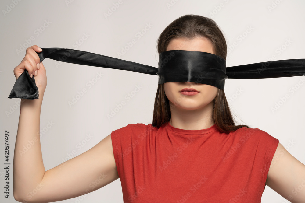 Young woman covering her eyes with black bound, isolated on white ...