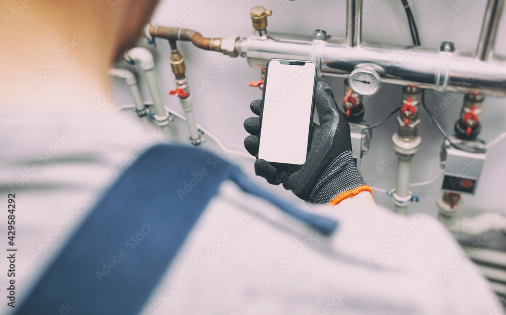 White blank screen mobile phone in plumber's hand in protection gloves ...