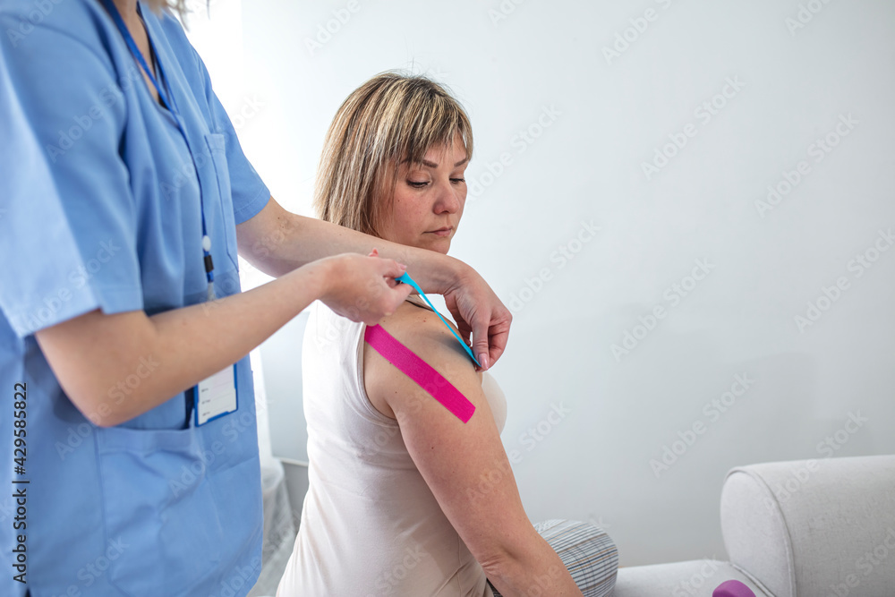 Kinesiotaping. Physical therapist applying tape to patient shoulder ...