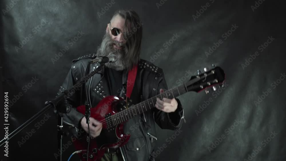 Bearded hairy rocker with shaved temples, round glasses and leather ...