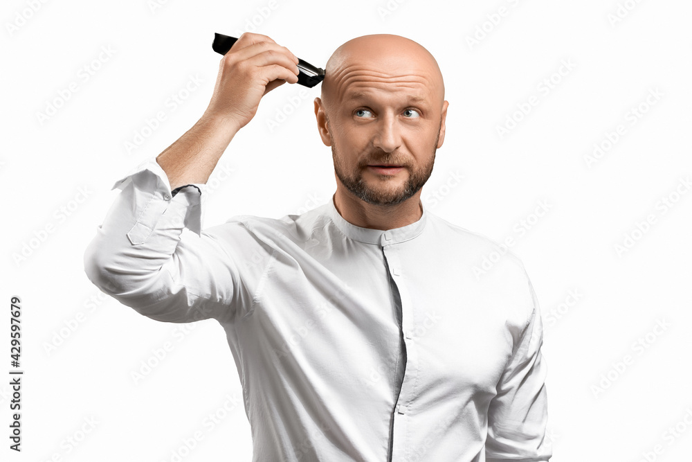 The concept of baldness and alopecia.A bearded man holds a hair clipper ...