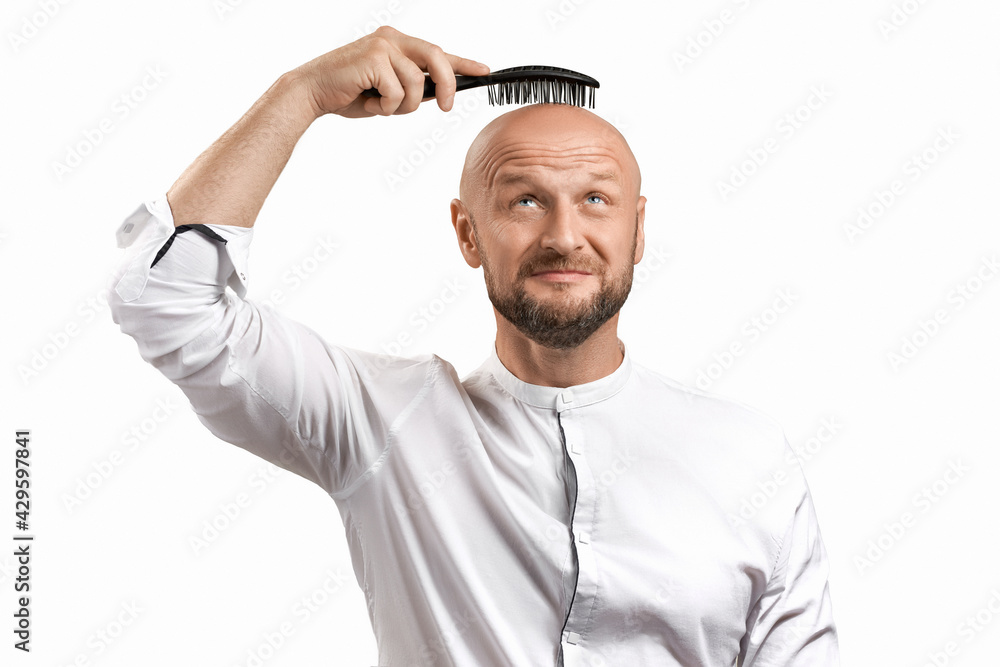 A sad bald man of forty years with a comb touches his bald head. Male ...