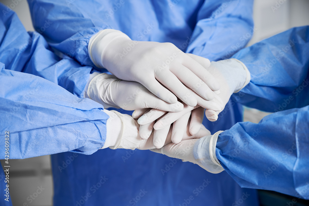 Close up of medical workers joining their hands together as symbol of ...