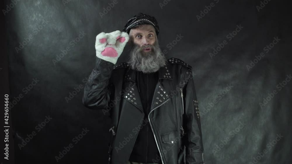Vidéo Stock Bearded rocker in leather jacket and cap smiling and waving ...