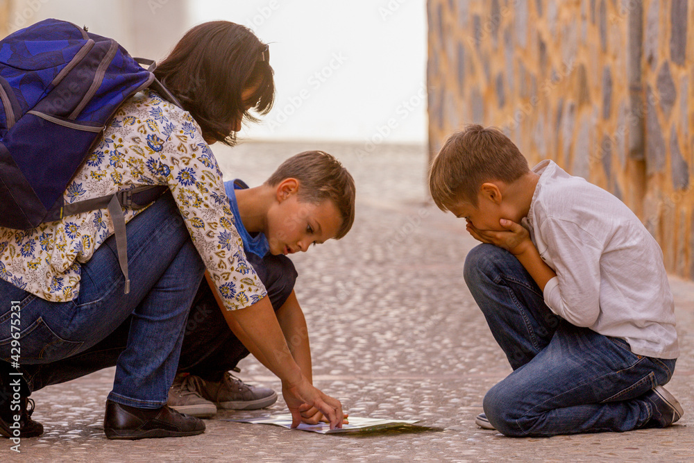 Mother with two kids looking at paper map to find destination in the ...
