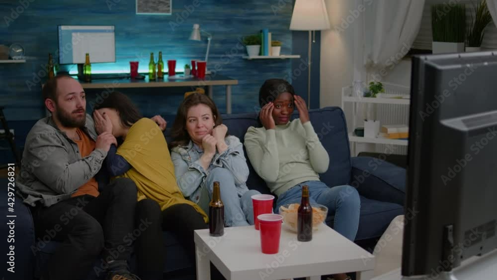 Multi-racial friends screaming while watching thriller horror movie ...