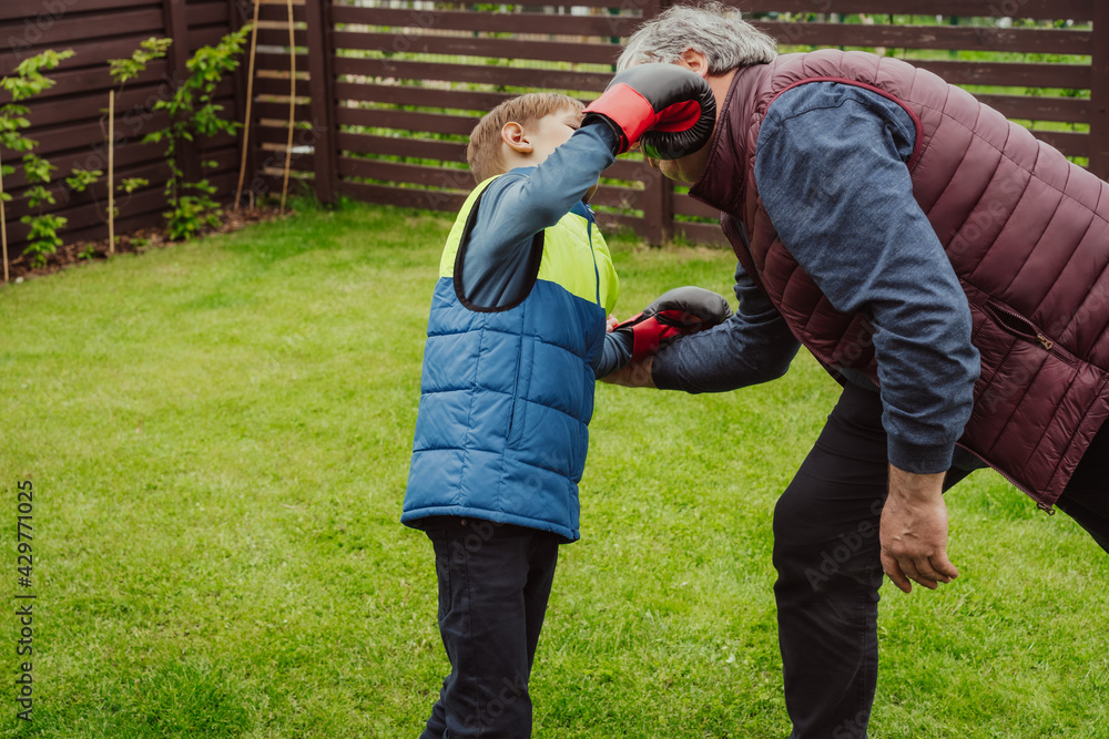 Grandad, dad teaching his child grandson boxing skills outdoors. Little ...