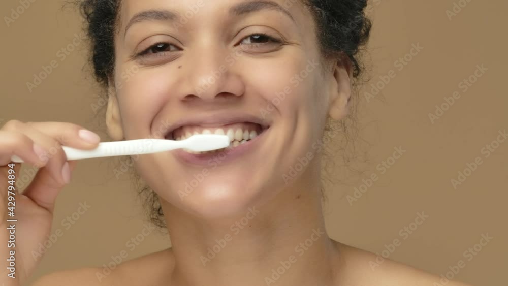 Beauty portrait of young African American woman is brushing her teeth ...