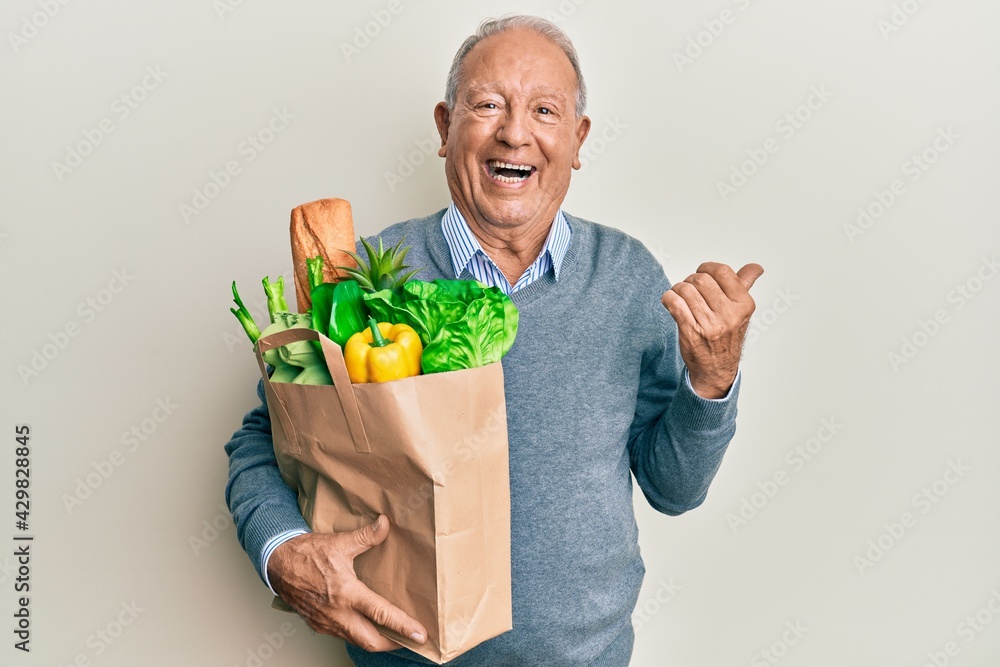 Senior caucasian man holding paper bag with bread and groceries ... Senior caucasian man holding paper bag with bread and groceries ...