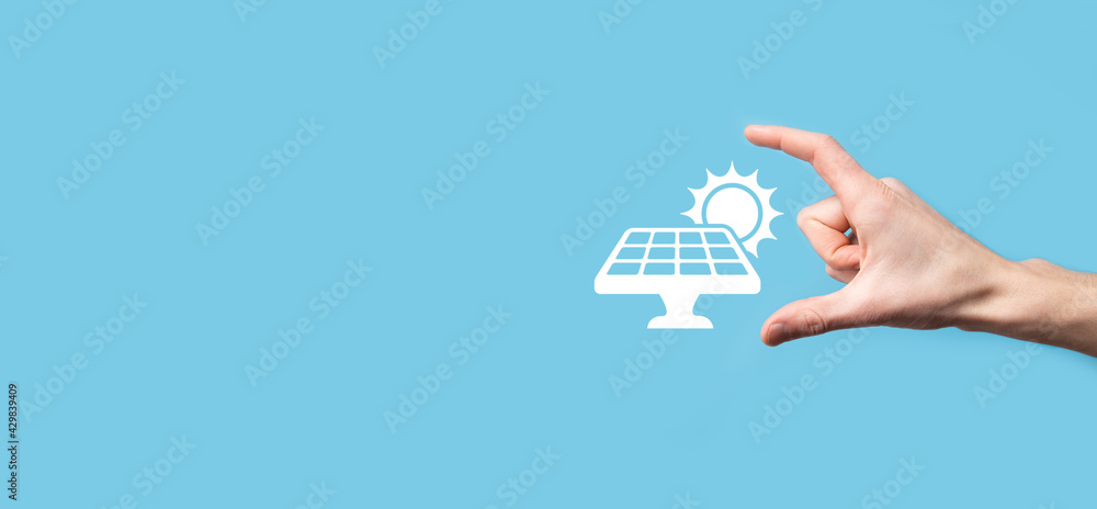 Hand on a blue background holds the icon symbol of solar panels ...