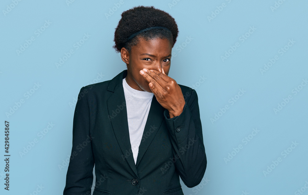 Young african american girl wearing business clothes smelling something ...