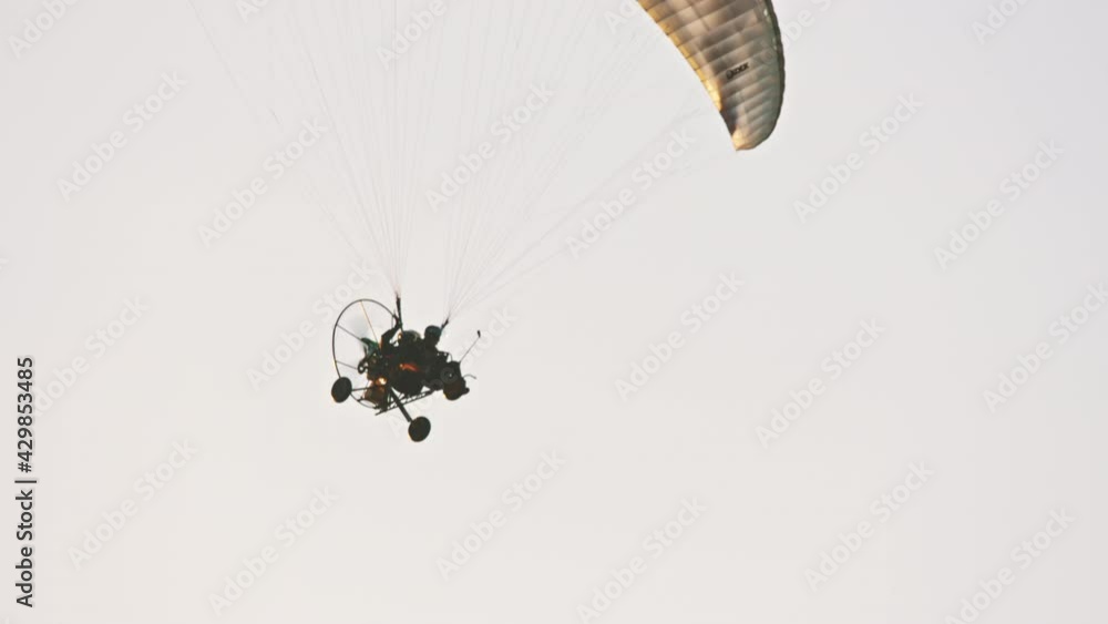 Flying Paramotor trike hanging under parachute. White sky background ...