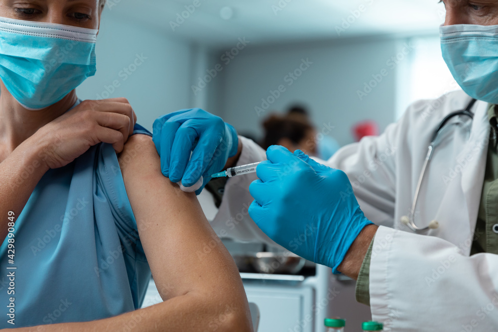 Caucasian male doctor giving covid vaccination to female colleague at ...
