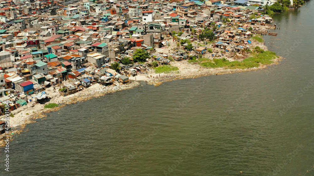 Slums with shacks of local residents and the river bank littered with ...