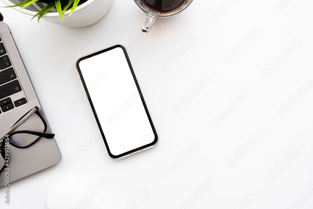 Smartphone with blank mockup screen is on top of white office desk ...