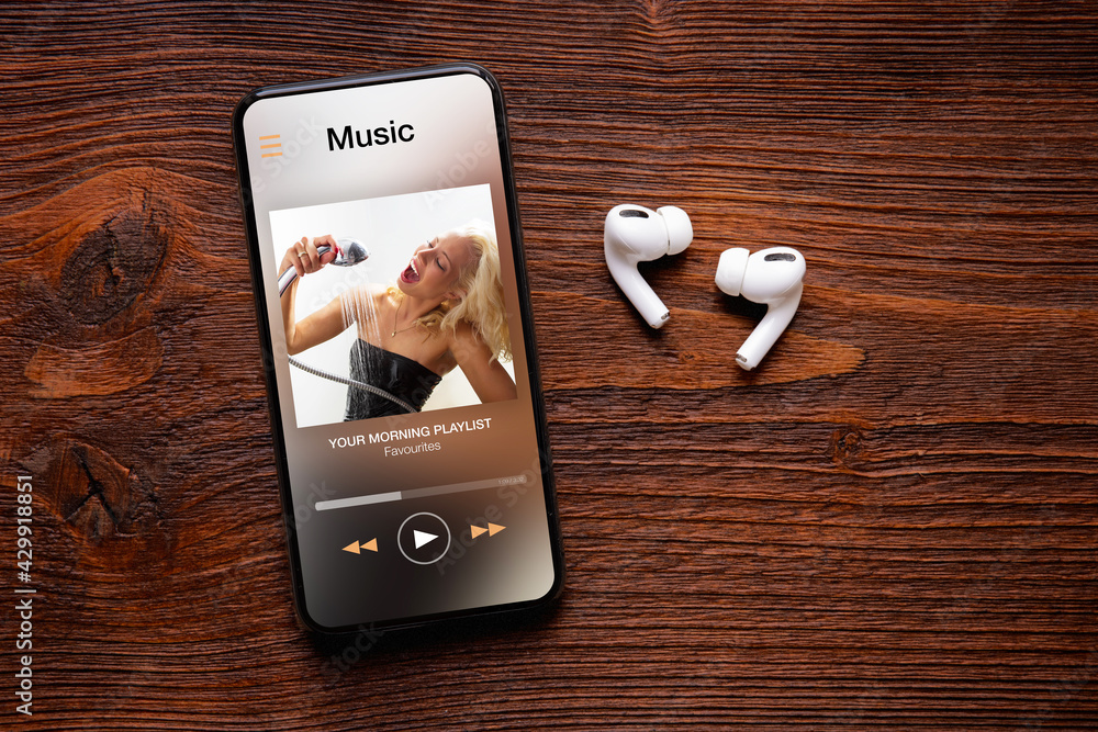 Foto de Music player on screen of mobile phone and wireless earbuds on ...