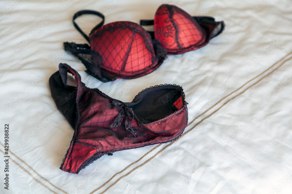 Beautiful lingerie is scattered on the bed. Women's lace red panties on ...