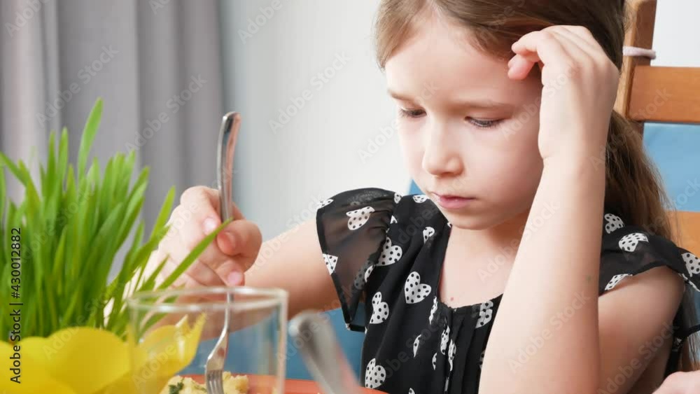 School age girl eating her meal sitting at the table at home, young ...