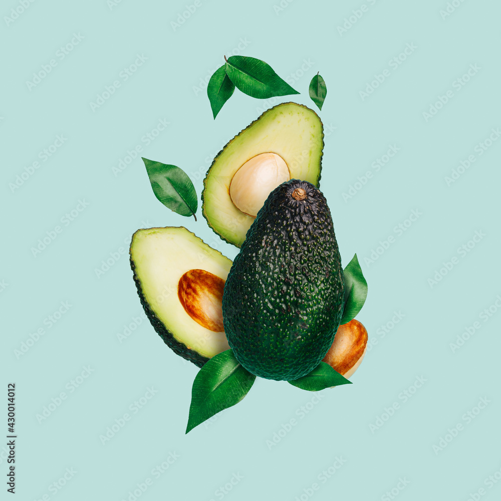 Flying fresh avocado with slices and leaves against pastel green ...