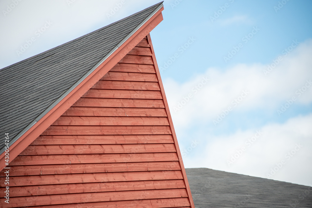 The exterior of a red wooden clapboard building with two angled pitched ...