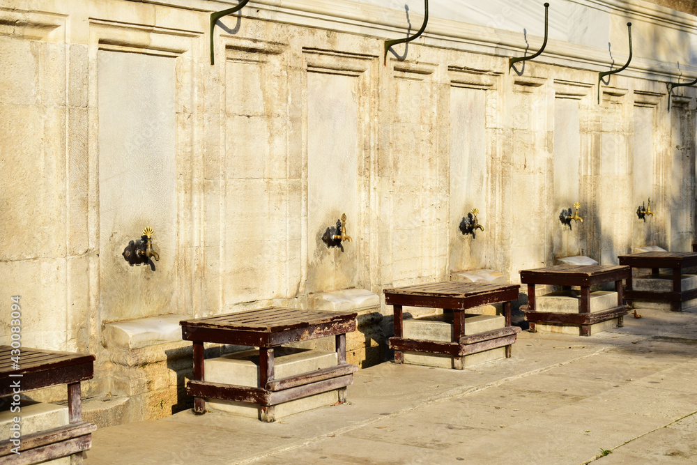 Water taps and wooden seats used for Islamic ritual washing or ablution ...