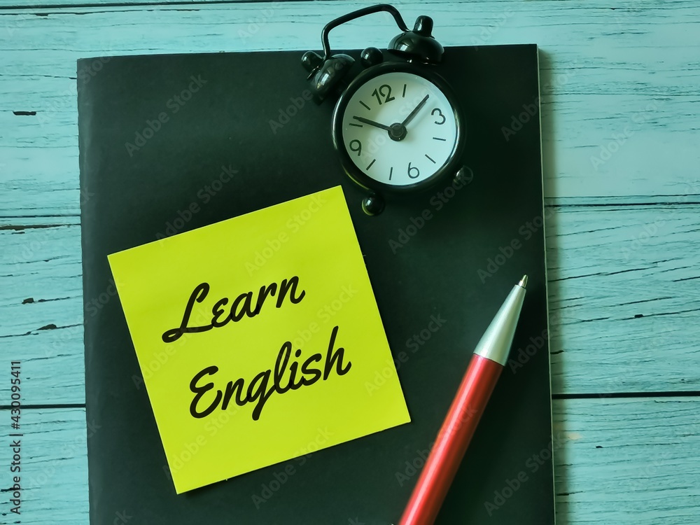 Phrase learn English written on sticky note with a pen,alarm clock and ...