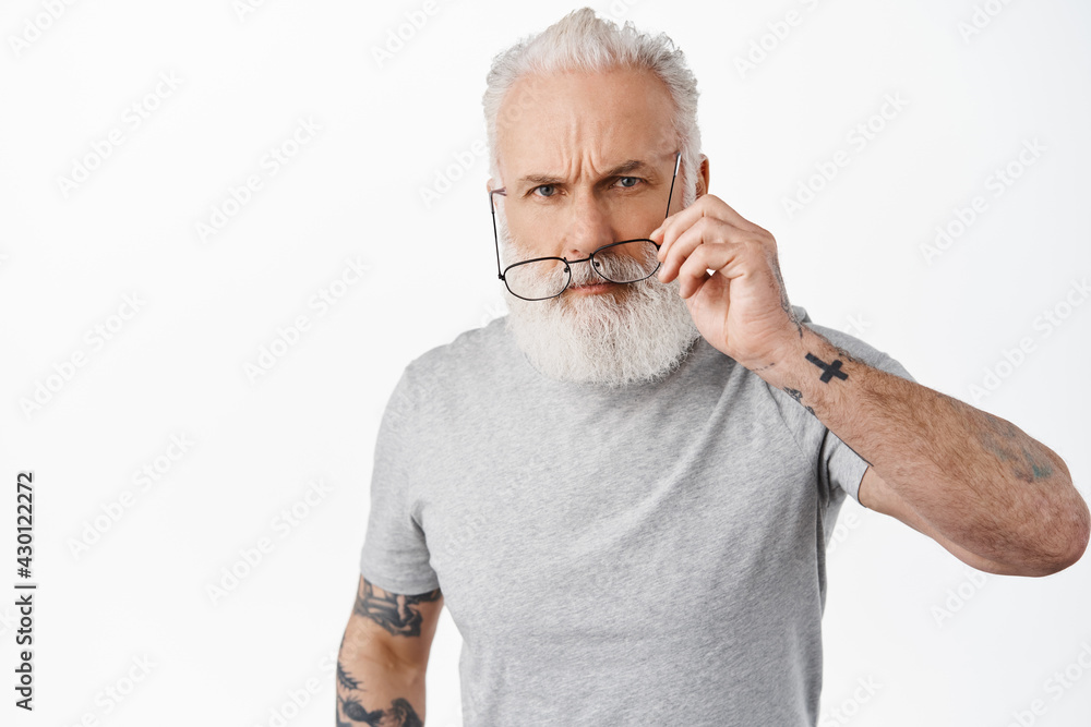 Suspicious old man with tattoos, take off glasses and looking with ...