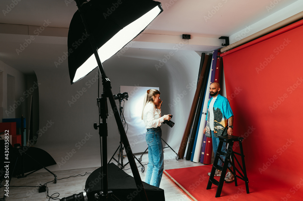 Woman photographer with a camera in her hands in a photo studio makes a ...