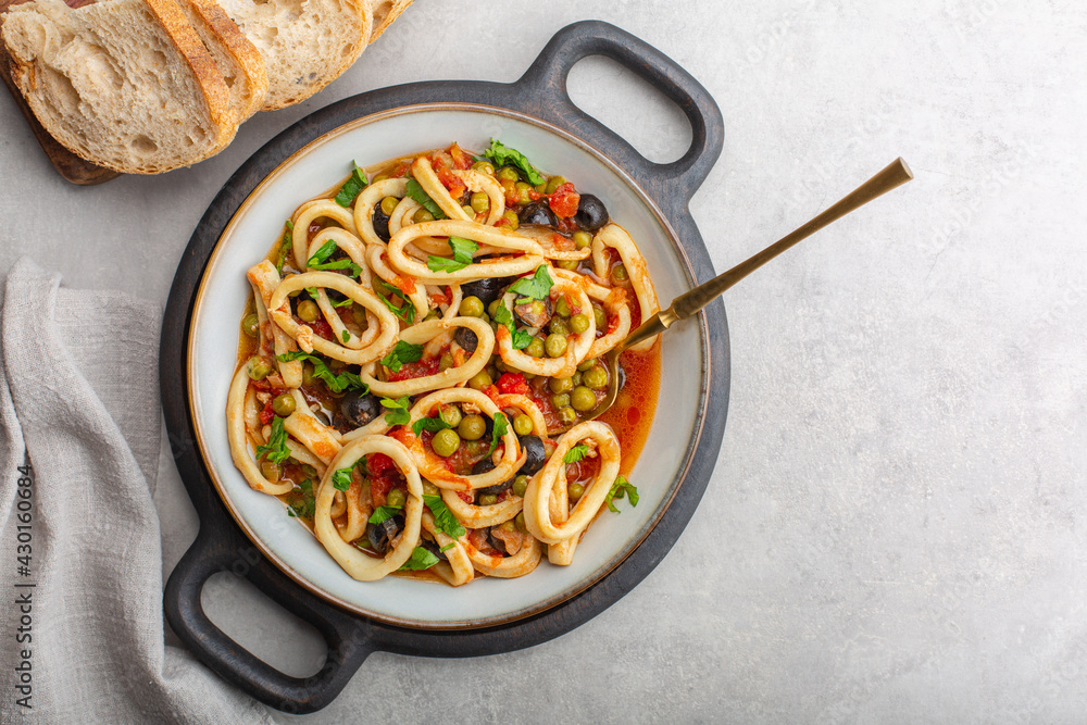 Italian dish - calamari in umido, squid braised in tomatoes, green peas ...