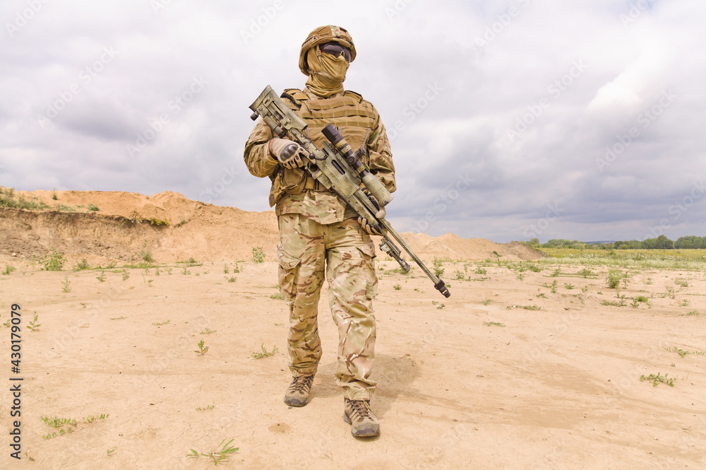 Fully equipped and armed soldier with rifle in the desert. Concept of ...