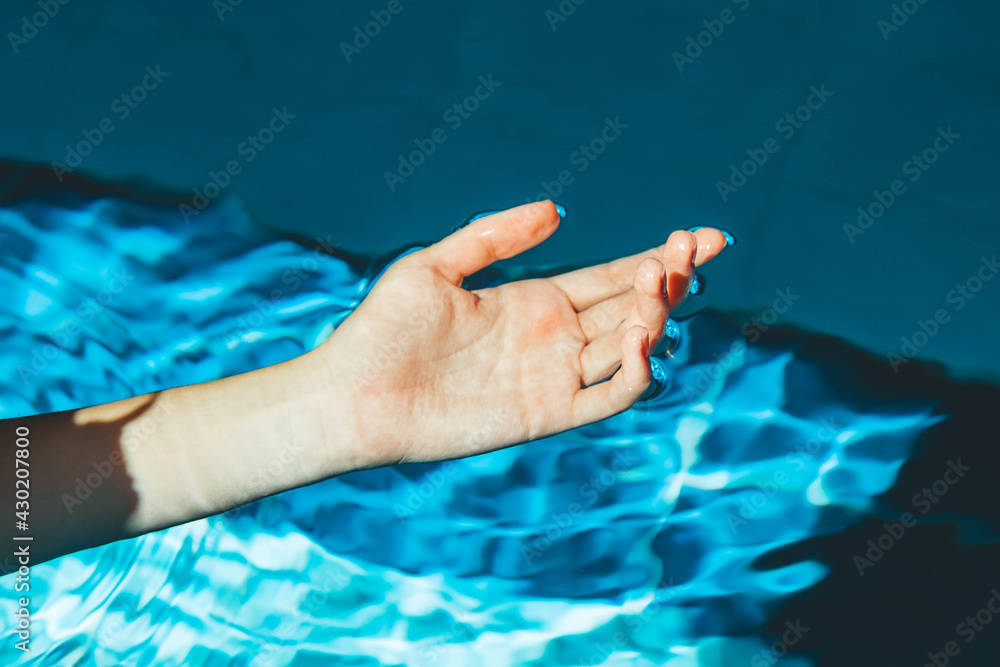 the swimmer's hand plunges into a water pool with blue transparent ...