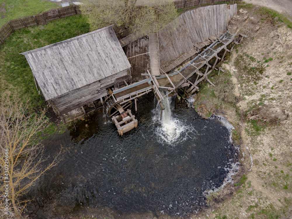 Water mill wheel rotates under a stream of water. Traditional village ...