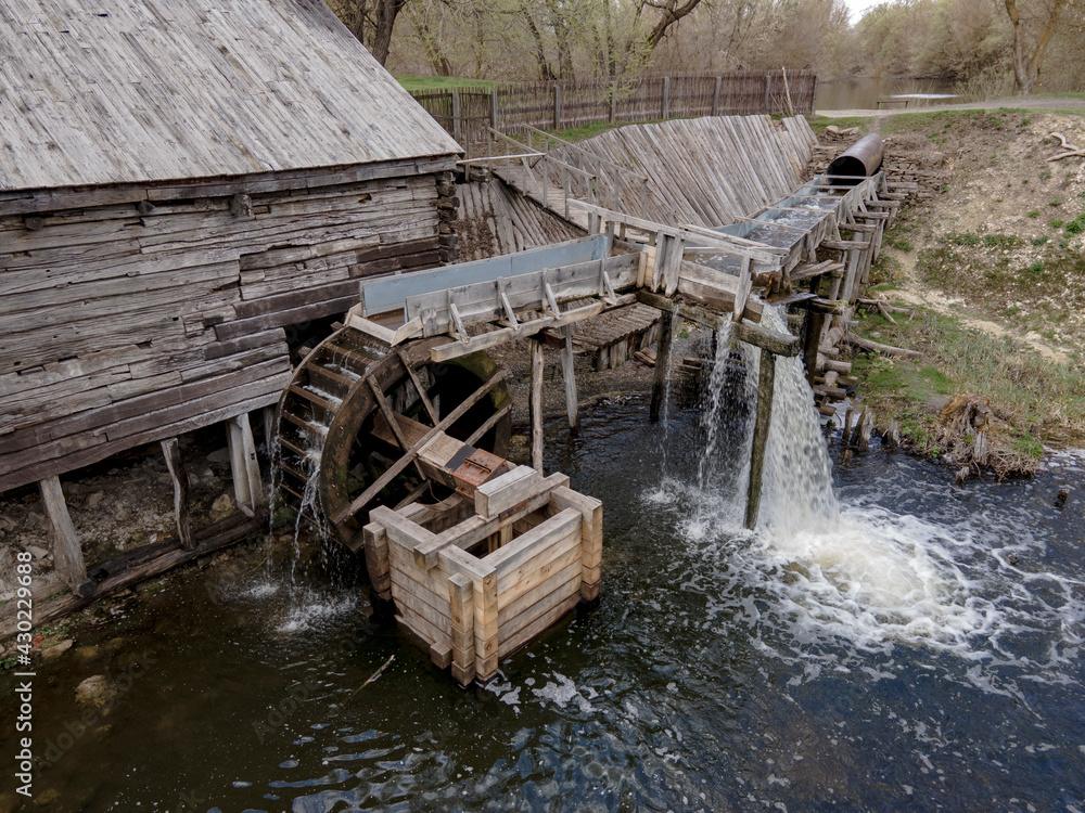 Foto de Water mill wheel rotates under a stream of water. Traditional ...