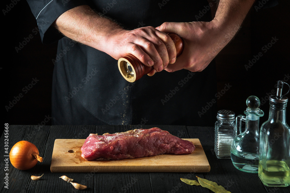 Chef cooking raw meat fillet and adding pepper and chili for marinade ...
