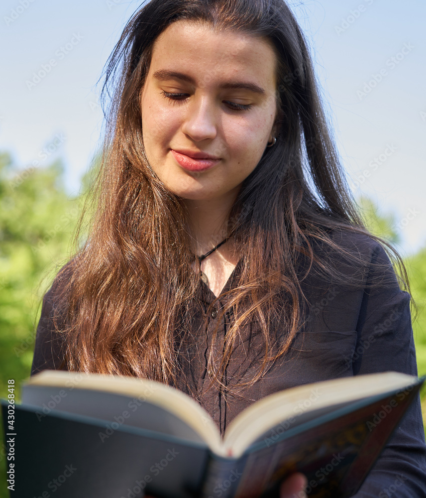 girl with fair skin and long hair, black shirt and white pants reading ...